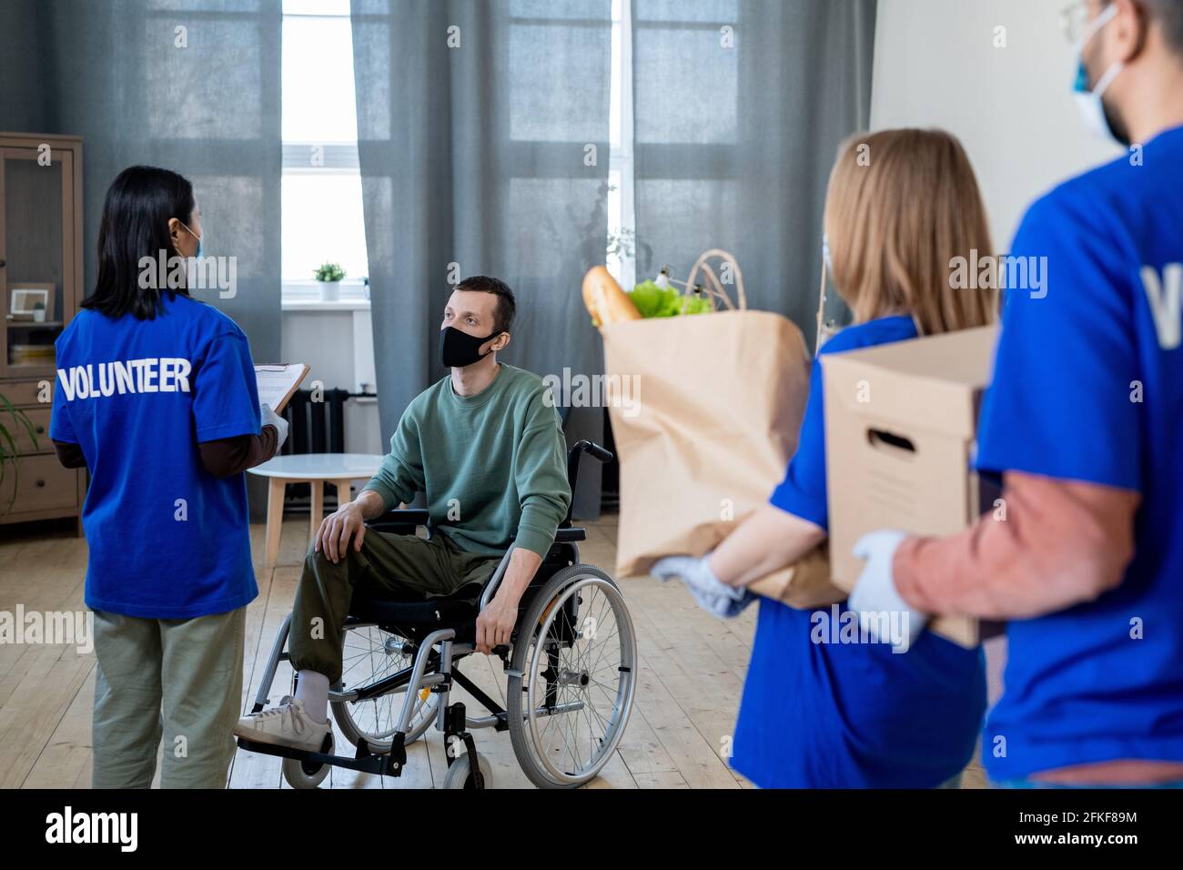 Disable guy in a wheelchair talking to a group of young volunteers ...