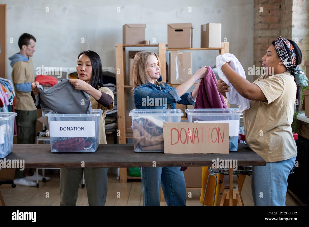 A group of people standing around a table with donation in boxes Stock ...