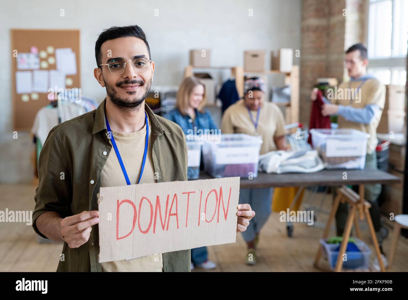 Young volunteer holding donation sign and looking at you Stock Photo ...