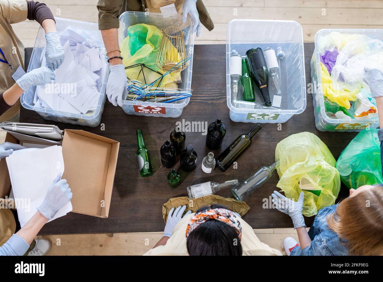 A group of volunteers sitting by table with plastic containers full of ...