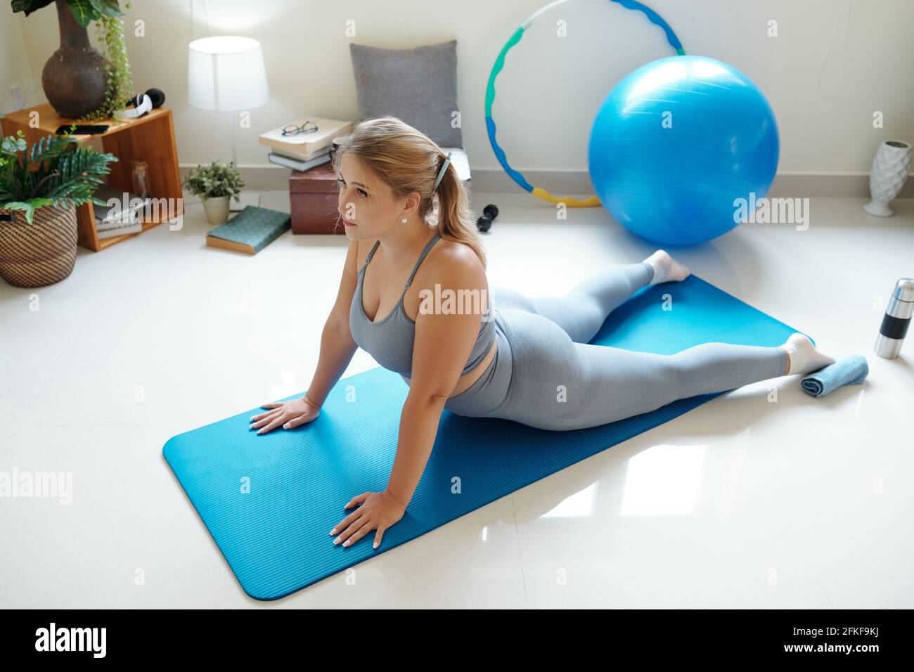 Plus size young woman doing exercises on yoga mat at home, she is ...