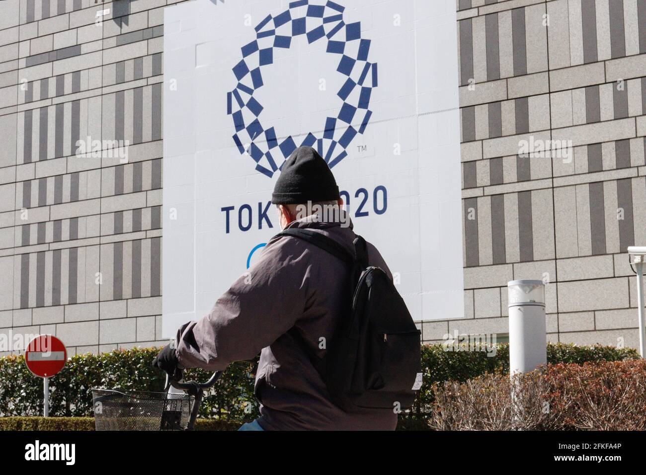 A pedestrian wearing a face mask as a precaution walks by a signage ...