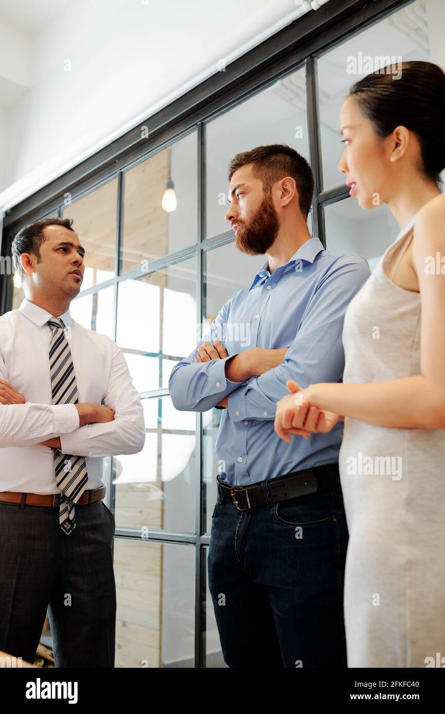 Frowning confident Indian entrepreneur talking to colleagues at meeting ...