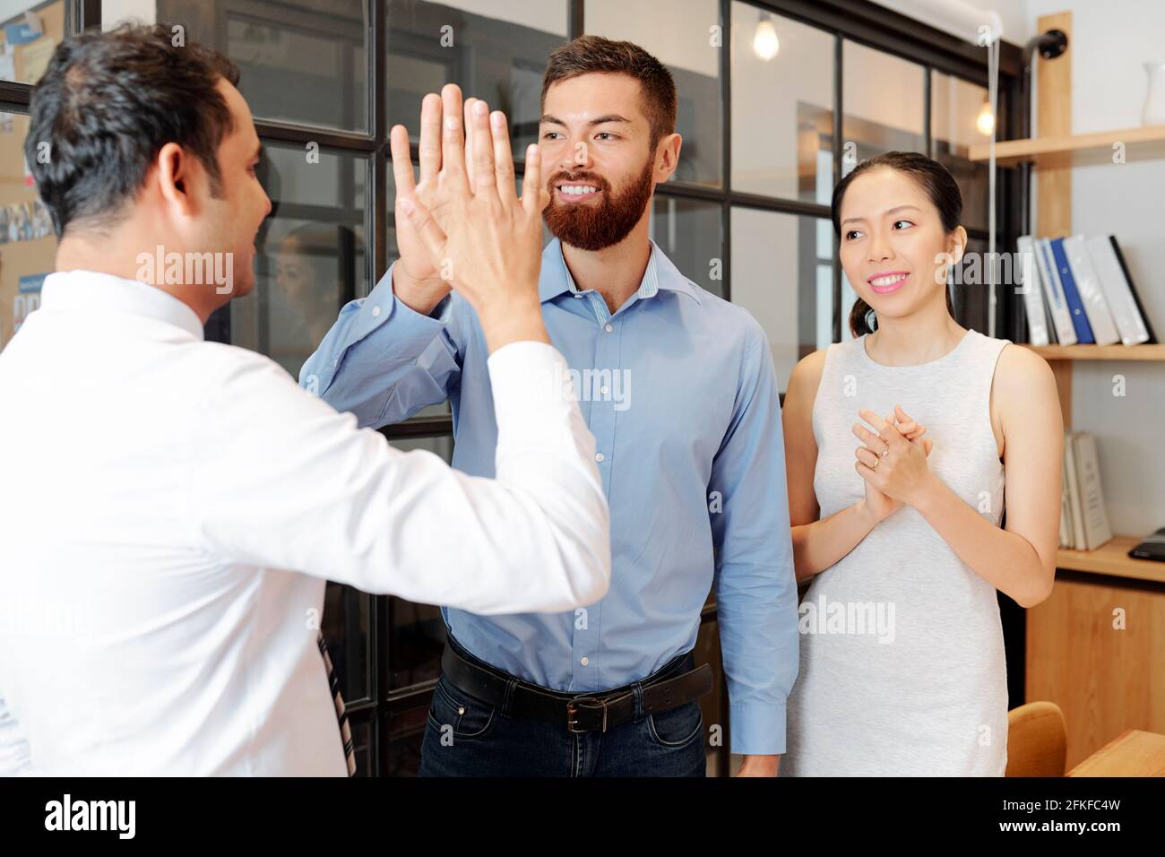 Smiling young businesswoman callping to colleagues giving each other ...