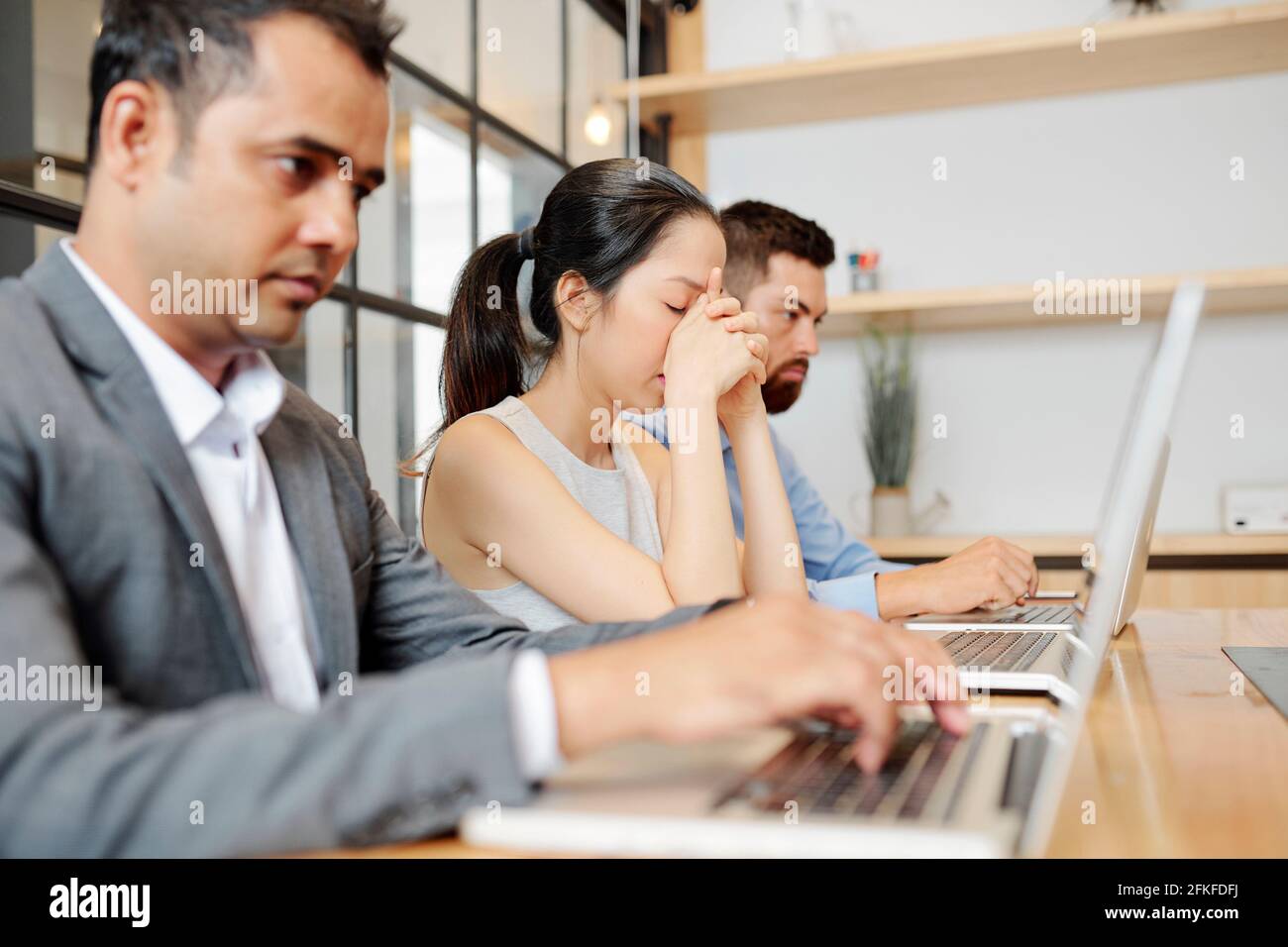 Stressed, frustrated almost crying young businesswoman sitting in front ...