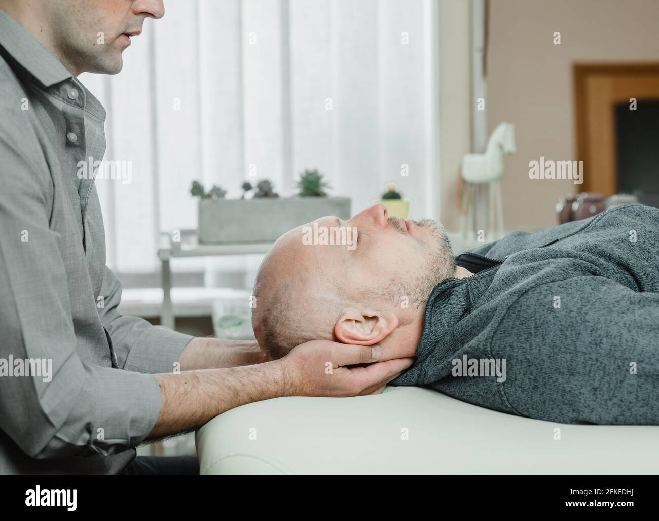 Craniosacral therapy practitioner giving a male patient CST osteopathic ...