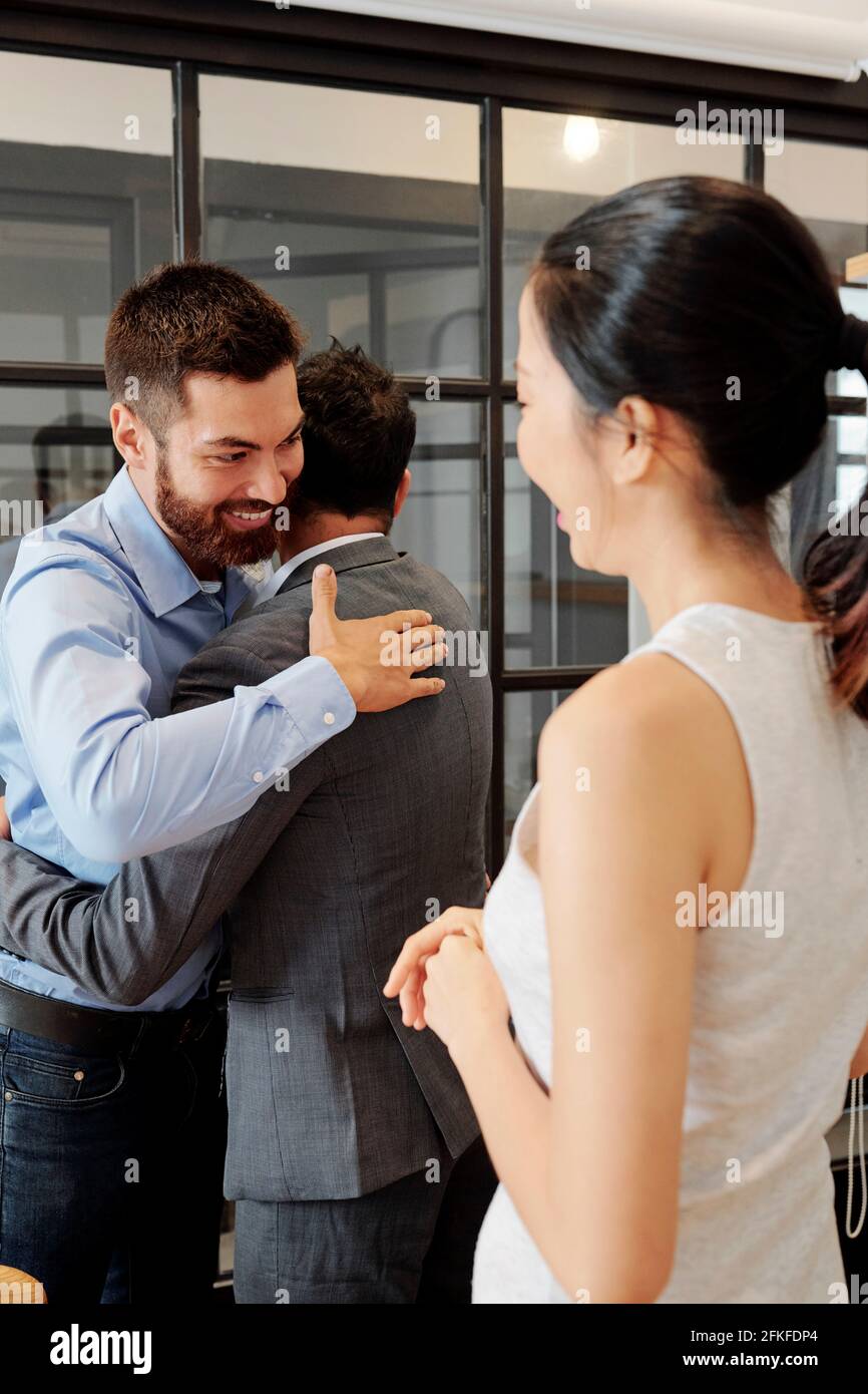 Happy excited business people hugging after finishing work on big ...