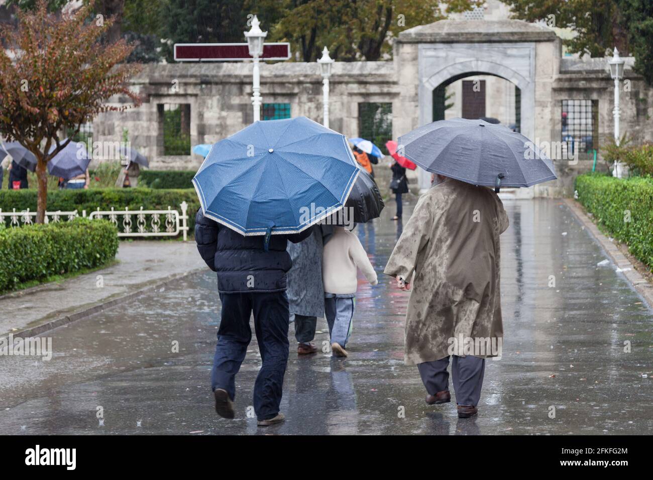 Tourists walk in the rain partially protected under umbrellas in ...