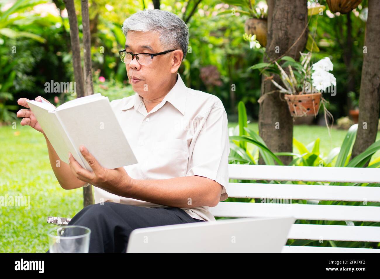 senior old man reading a book in the park and drinking water. Concept ...