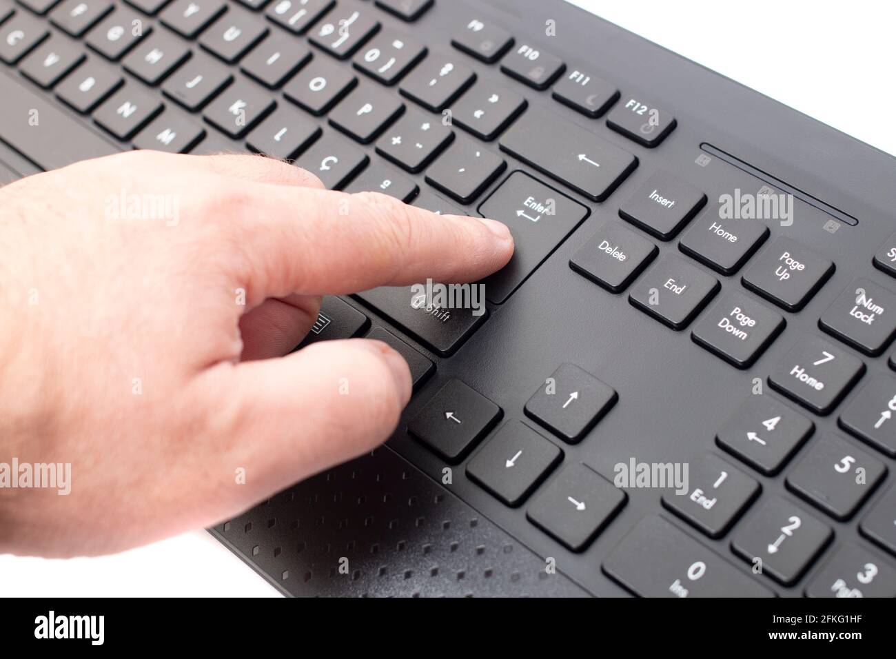Finger pushes enter key on a wireless black personal computer keyboard ...