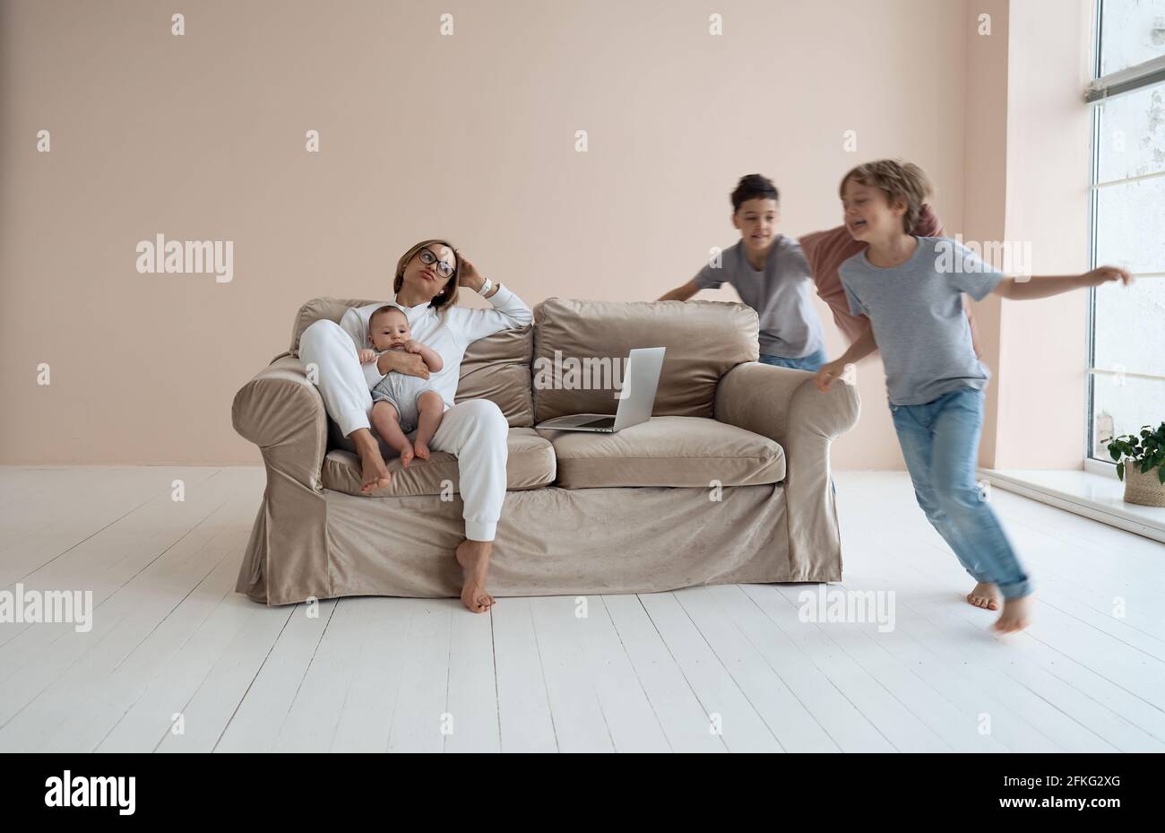 Young Single Mother Working On Laptop In Loft Sitting On Couch While