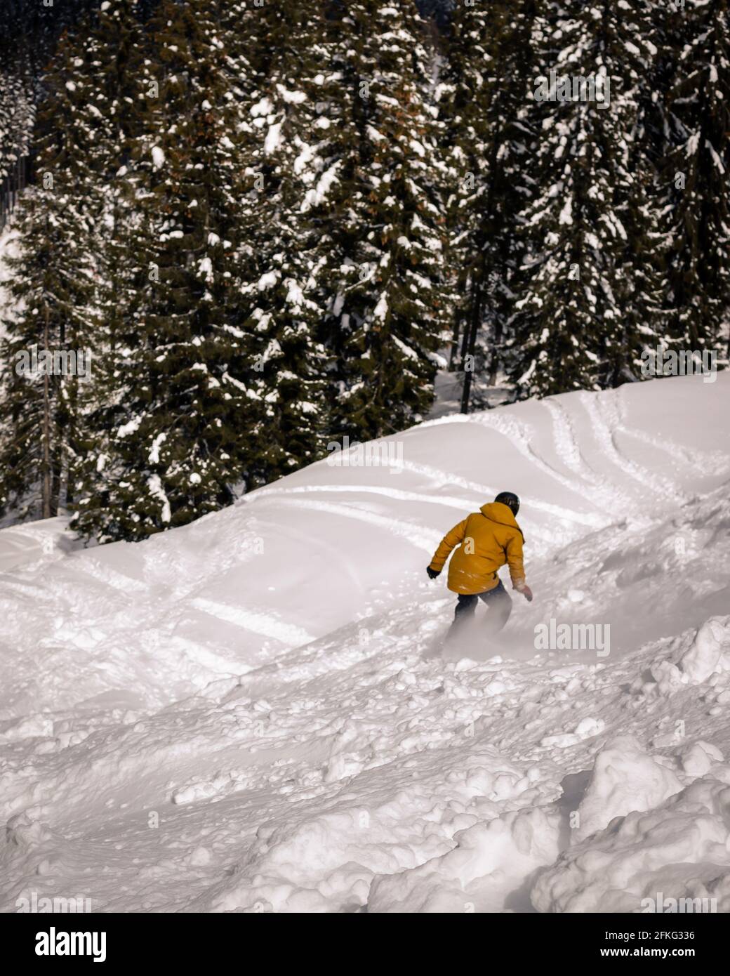 Vertical shot of an adult person with a helmet snowboarding on the ...
