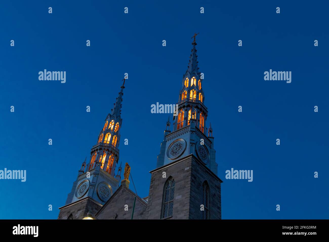 Gothic church spires lit up at night with a clear blue sky background ...