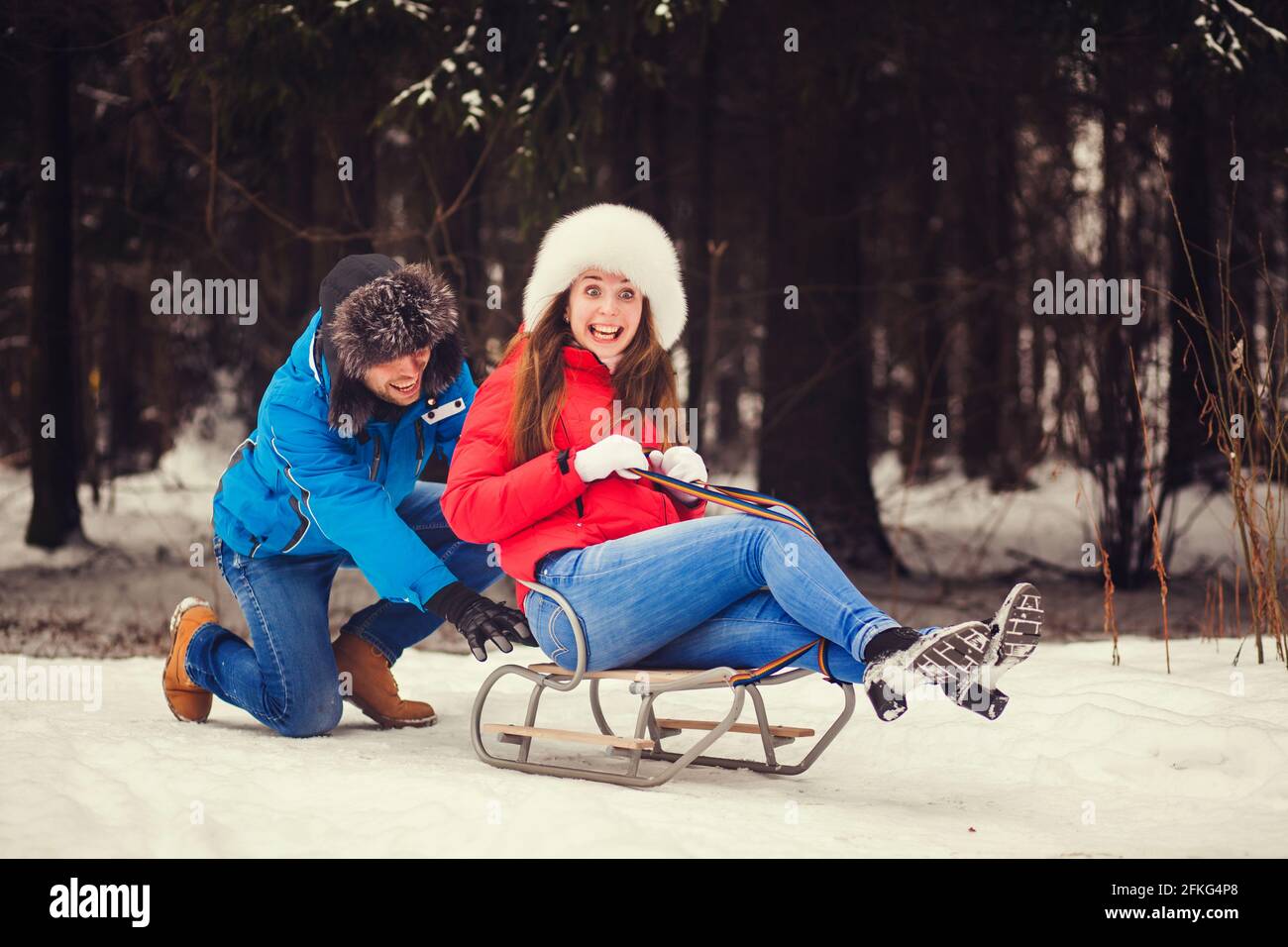 Positive couple sledding in winter park on Valentine's Day Stock Photo ...