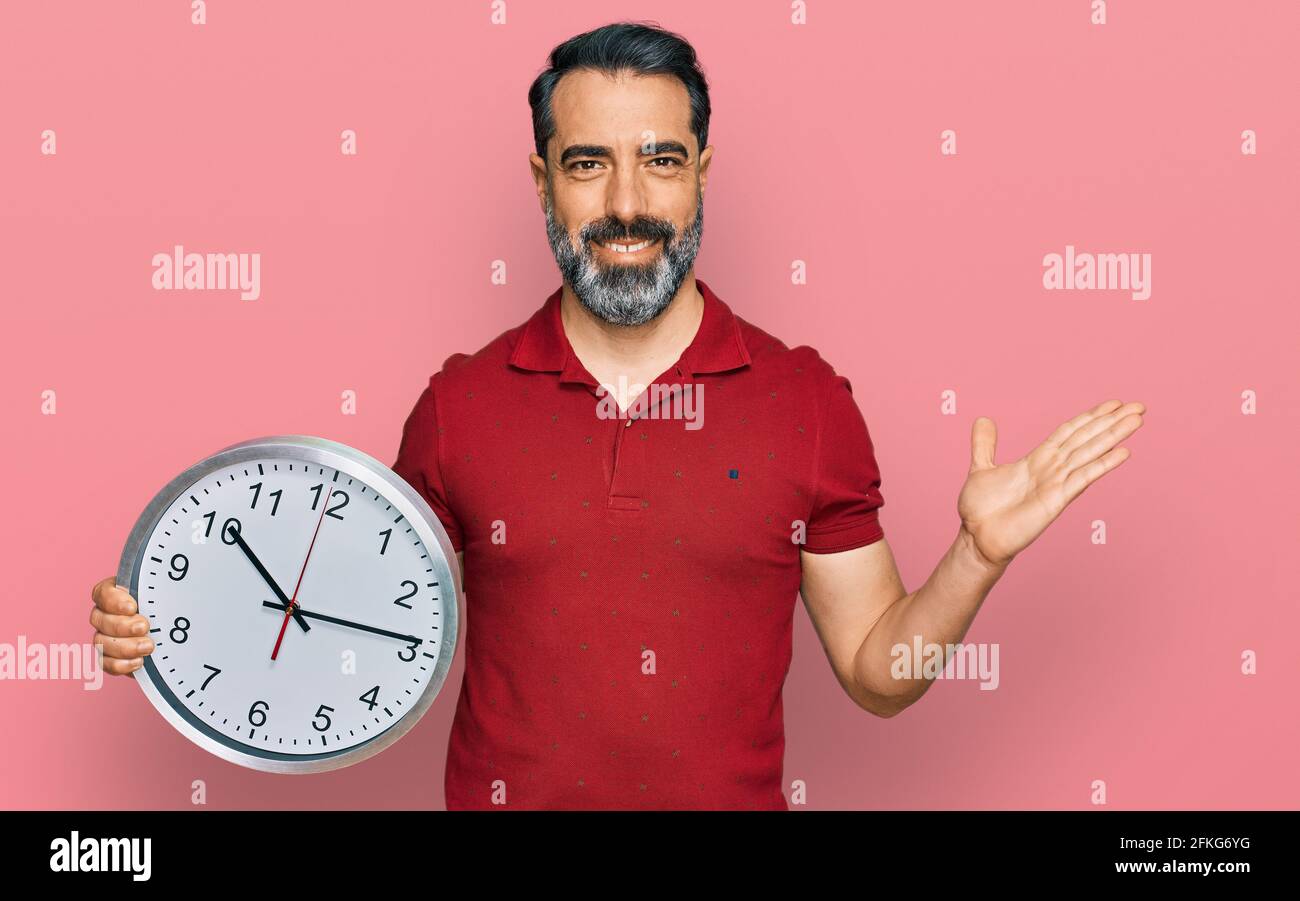 Middle aged man with beard holding big clock celebrating victory with ...