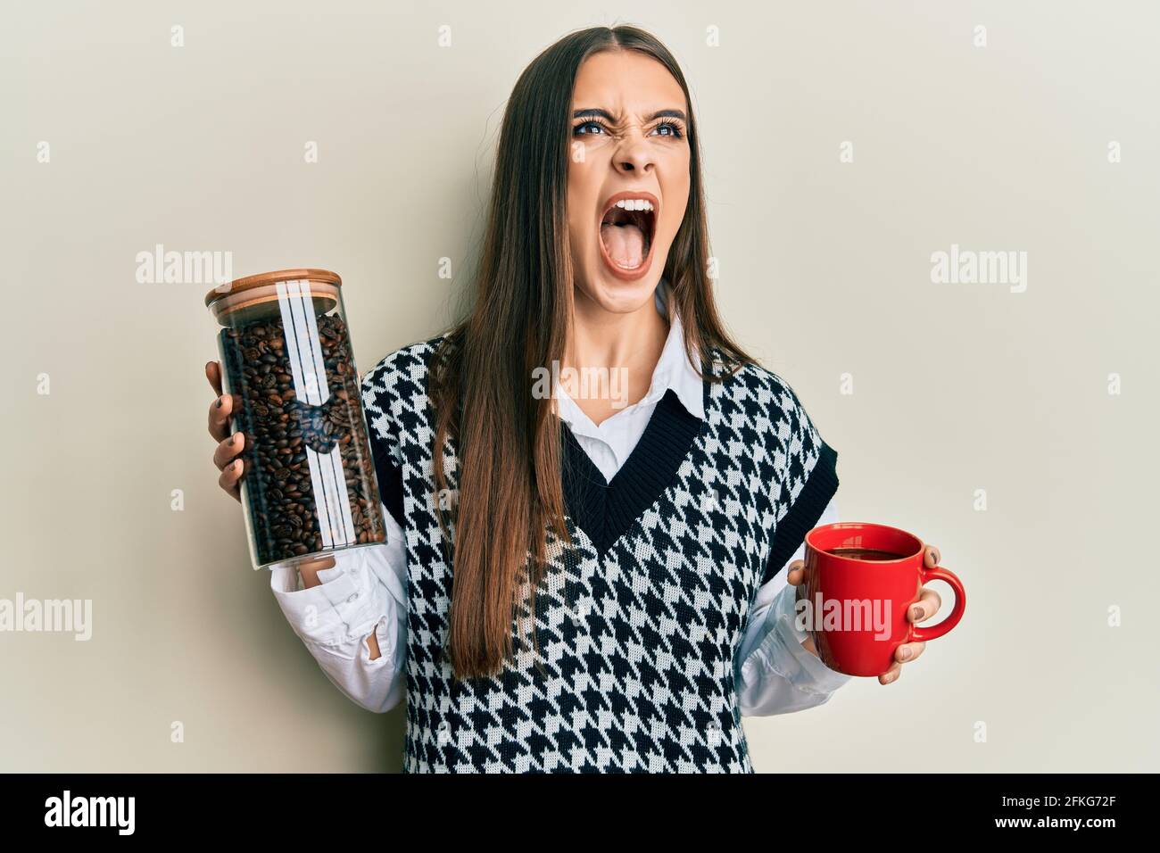 Beautiful brunette young woman holding jar with coffee beans and ...