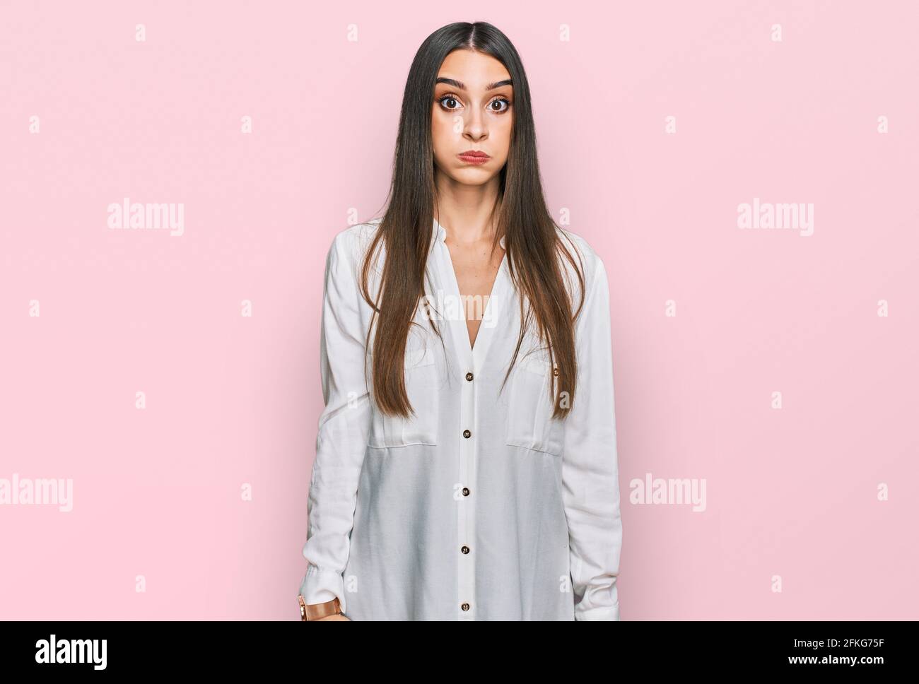 Young beautiful woman wearing casual white shirt puffing cheeks with ...