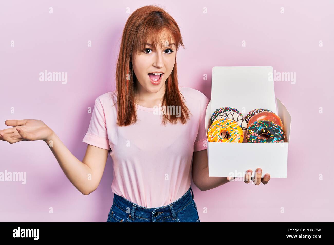 Redhead young woman holding tasty colorful doughnuts celebrating ...