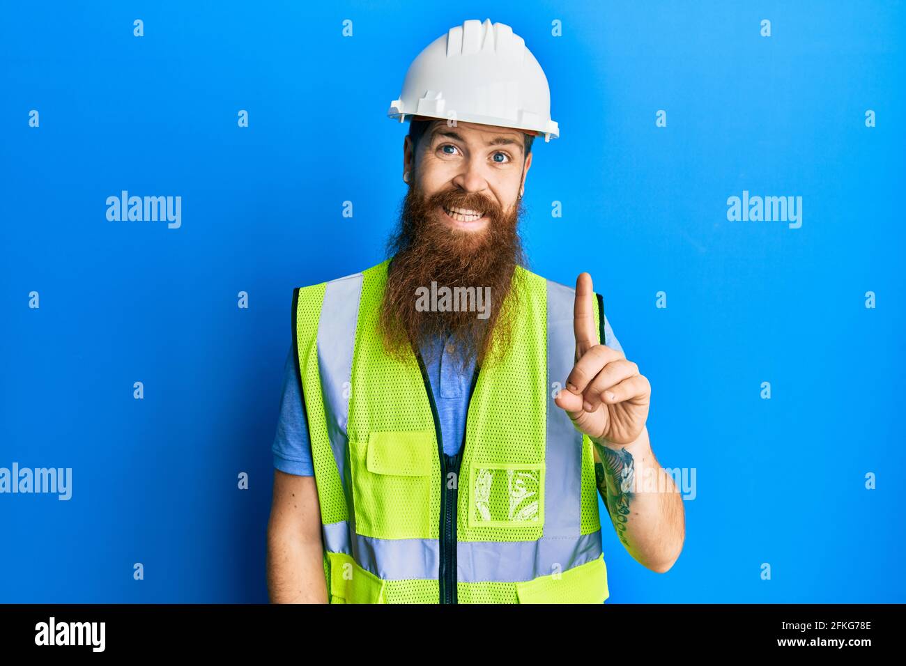 Redhead man with long beard wearing safety helmet and reflective jacket ...