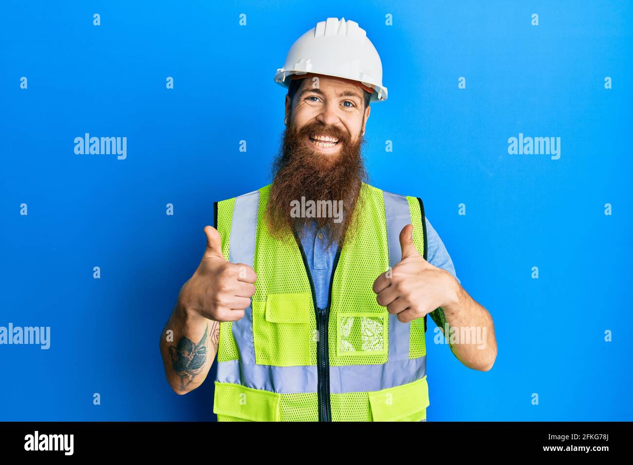 Redhead man with long beard wearing safety helmet and reflective jacket ...
