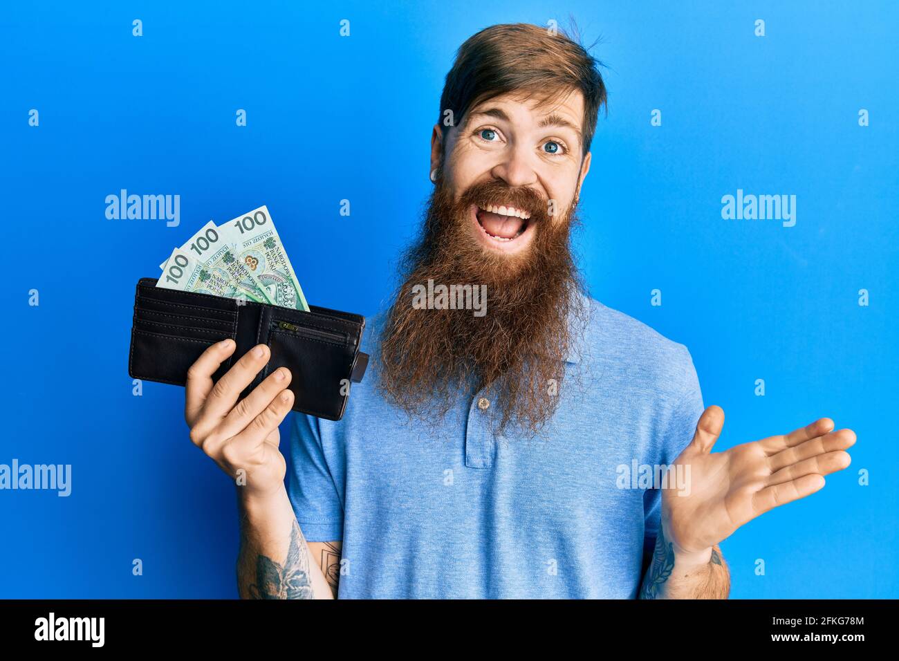 Redhead man with long beard holding wallet with polish zloty banknotes ...