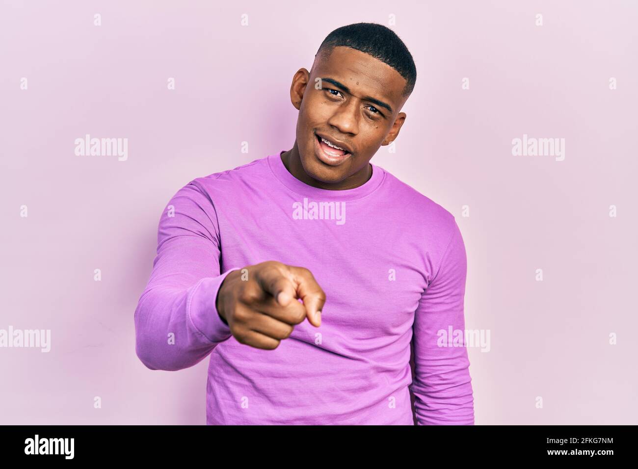 Young black man wearing casual pink sweater pointing displeased and ...