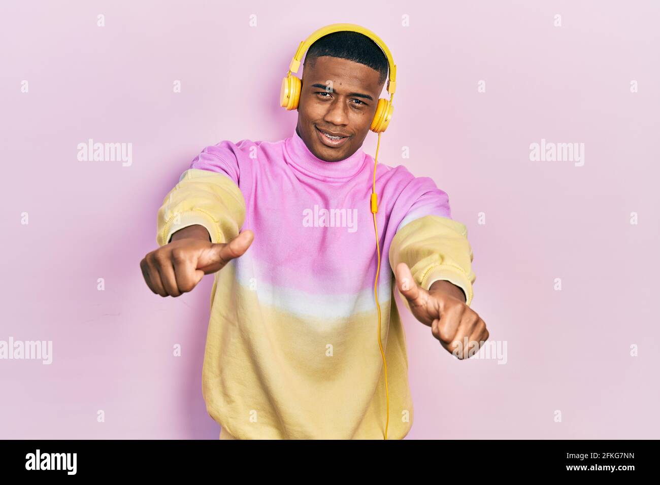 Young black man listening to music wearing headphones approving doing ...