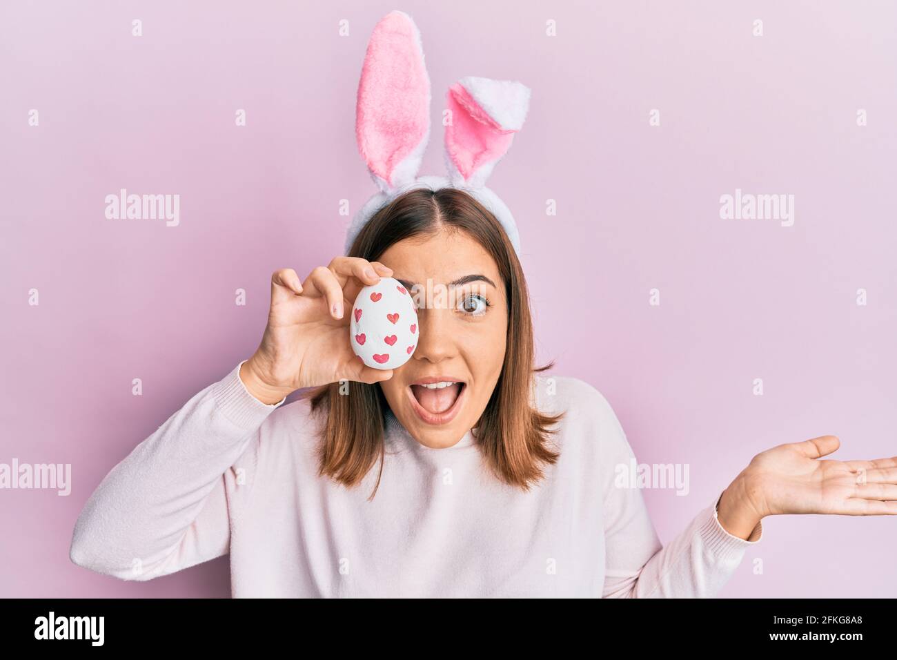 Young beautiful woman wearing cute easter bunny ears holding egg ...