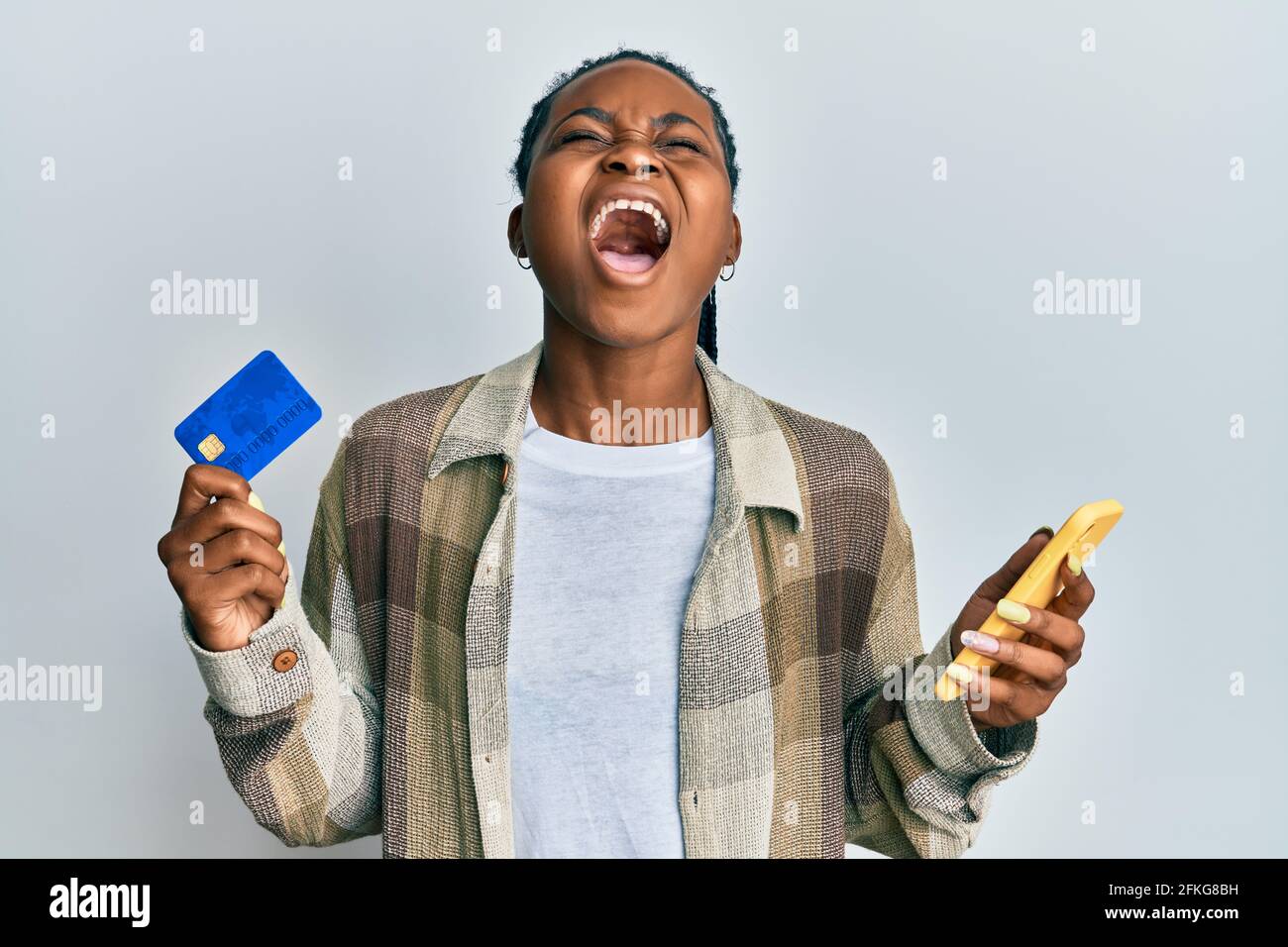 Young african american woman holding smartphone and credit card angry ...