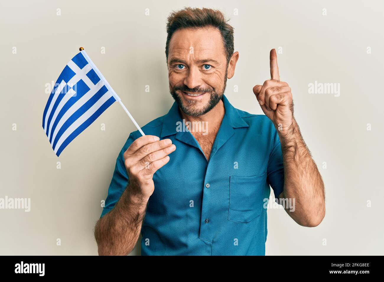 Middle age man holding greece flag smiling with an idea or question ...