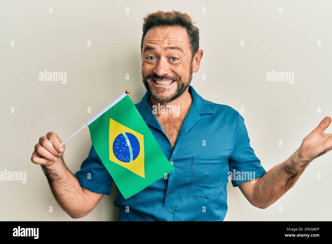 Middle age man holding brazil flag celebrating achievement with happy ...