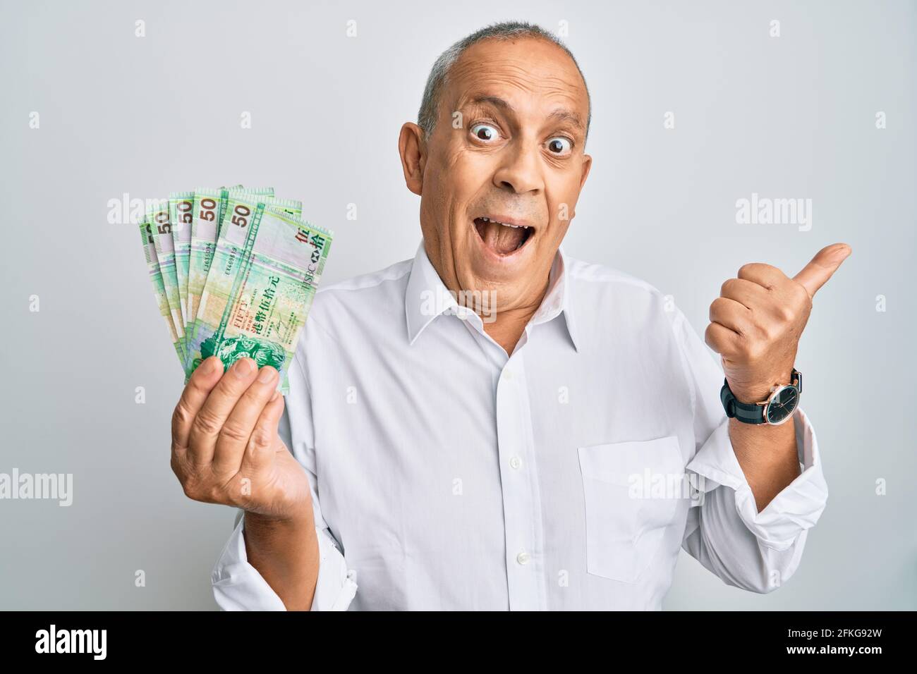 Handsome senior man holding 50 hong kong dollars banknotes pointing ...