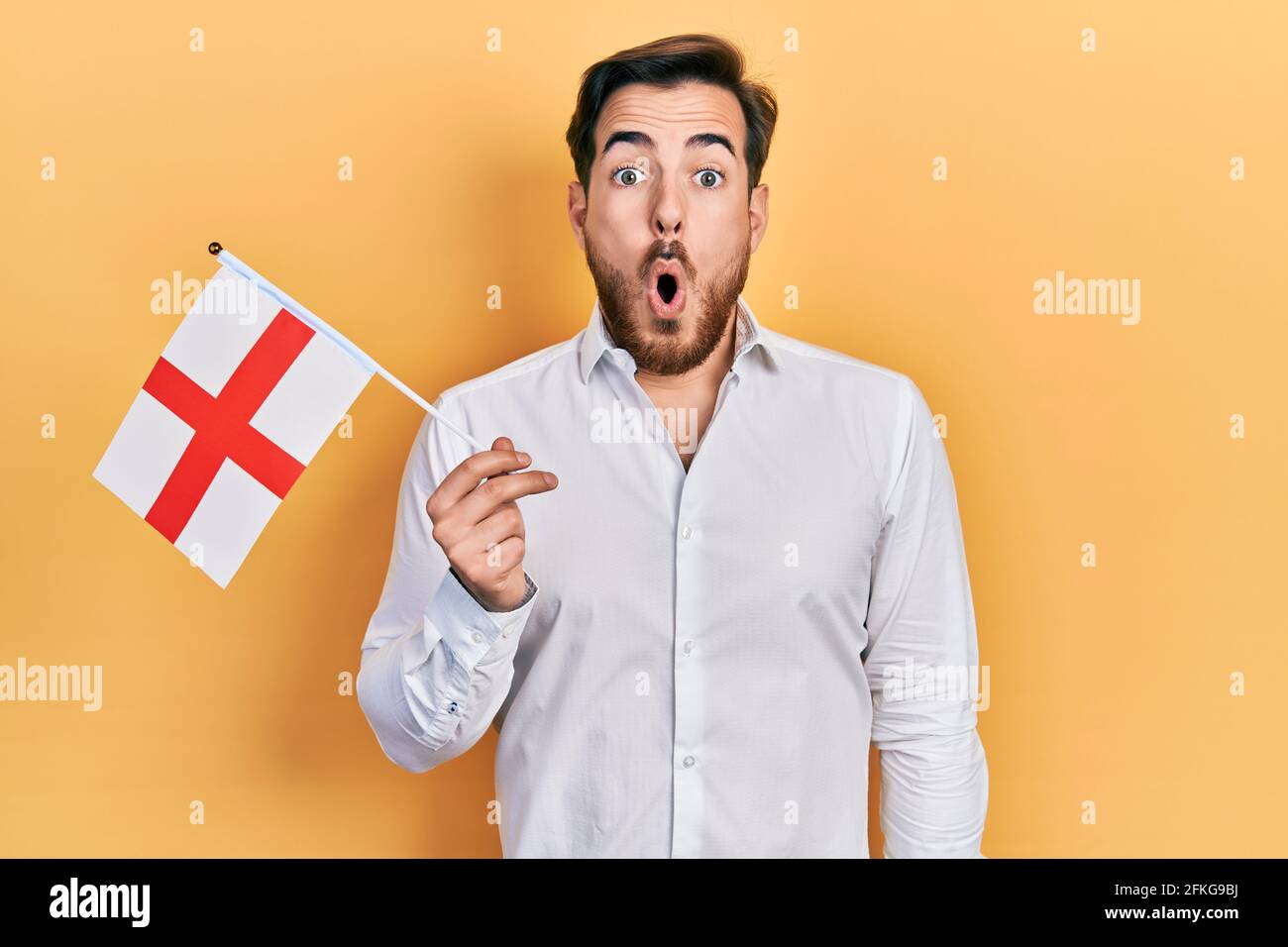 Handsome caucasian man with beard holding england flag scared and ...