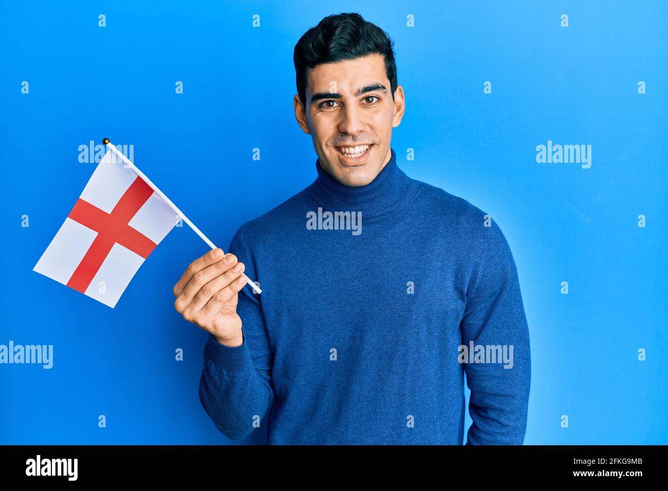 Handsome hispanic man holding england flag looking positive and happy ...