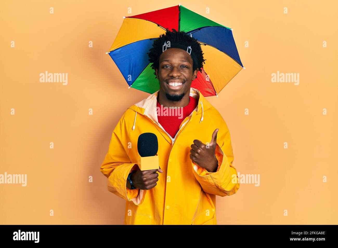Young african american journalist man wearing yellow raincoat and ...