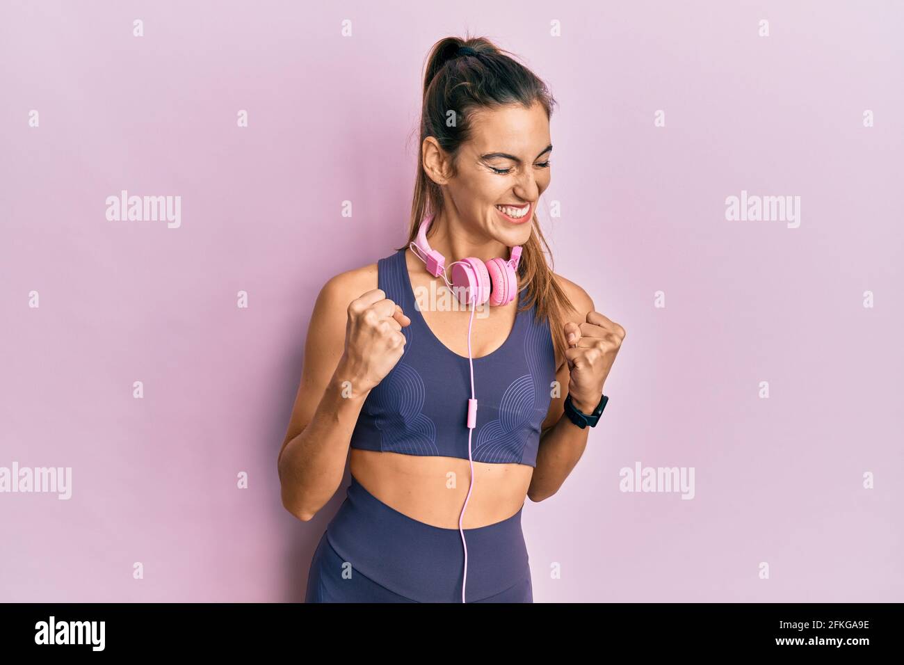 Young beautiful woman wearing gym clothes and using headphones excited ...