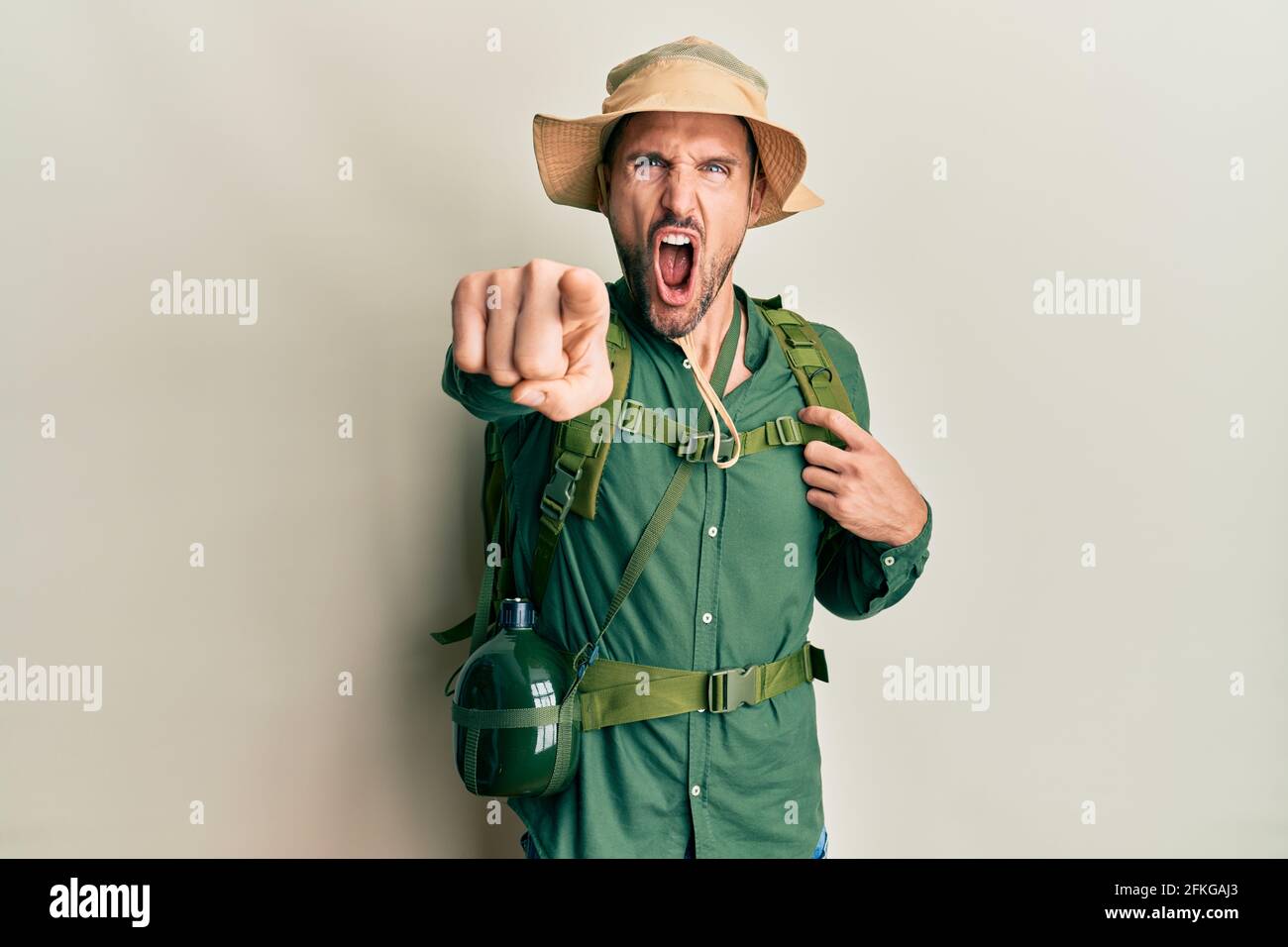 Handsome man with beard wearing explorer hat and backpack pointing ...