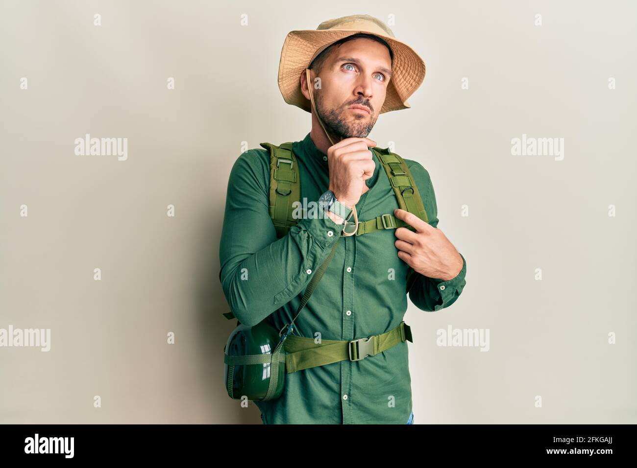 Handsome man with beard wearing explorer hat and backpack with hand on ...
