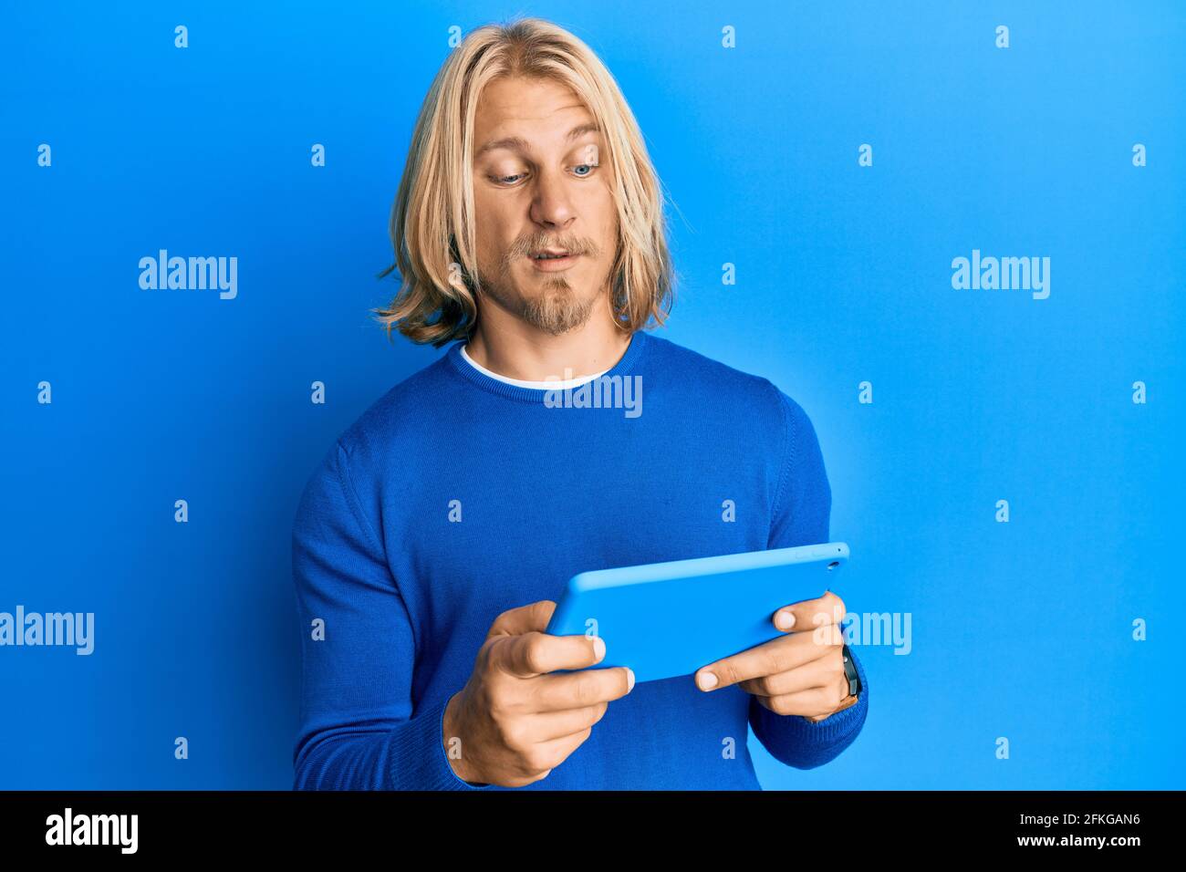 Caucasian young man with long hair using touchpad device clueless and ...