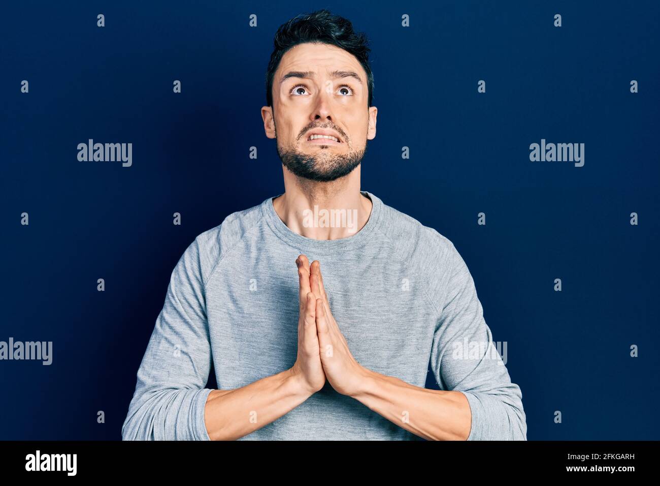 Young hispanic man wearing casual clothes begging and praying with ...