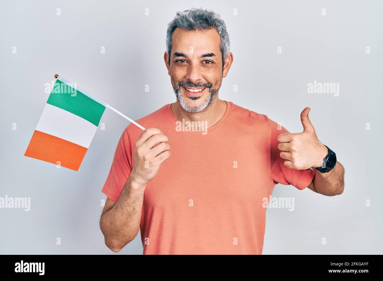 Handsome middle age man with grey hair holding ireland flag smiling ...