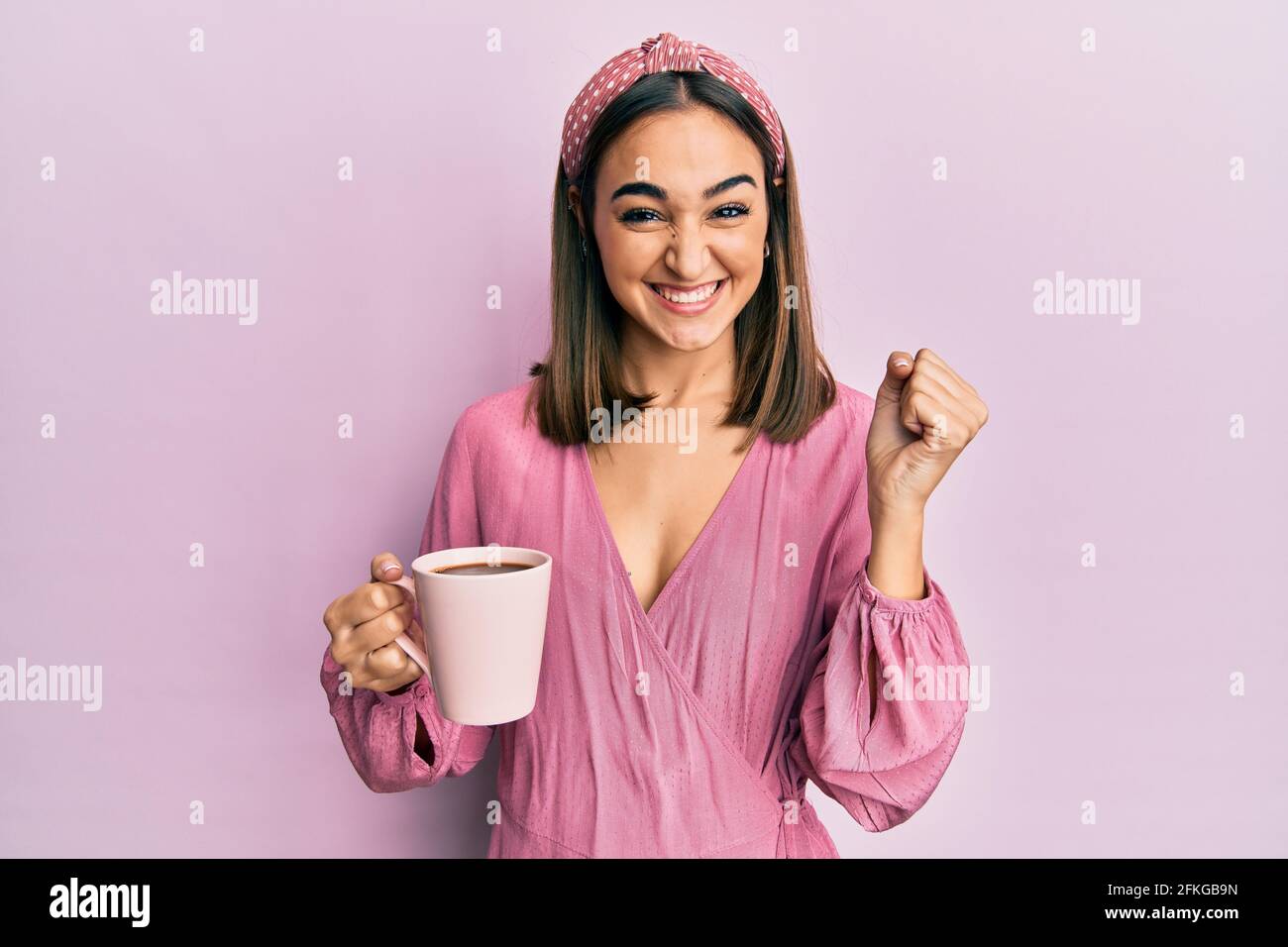 Young brunette girl drinking a cup of coffee screaming proud ...