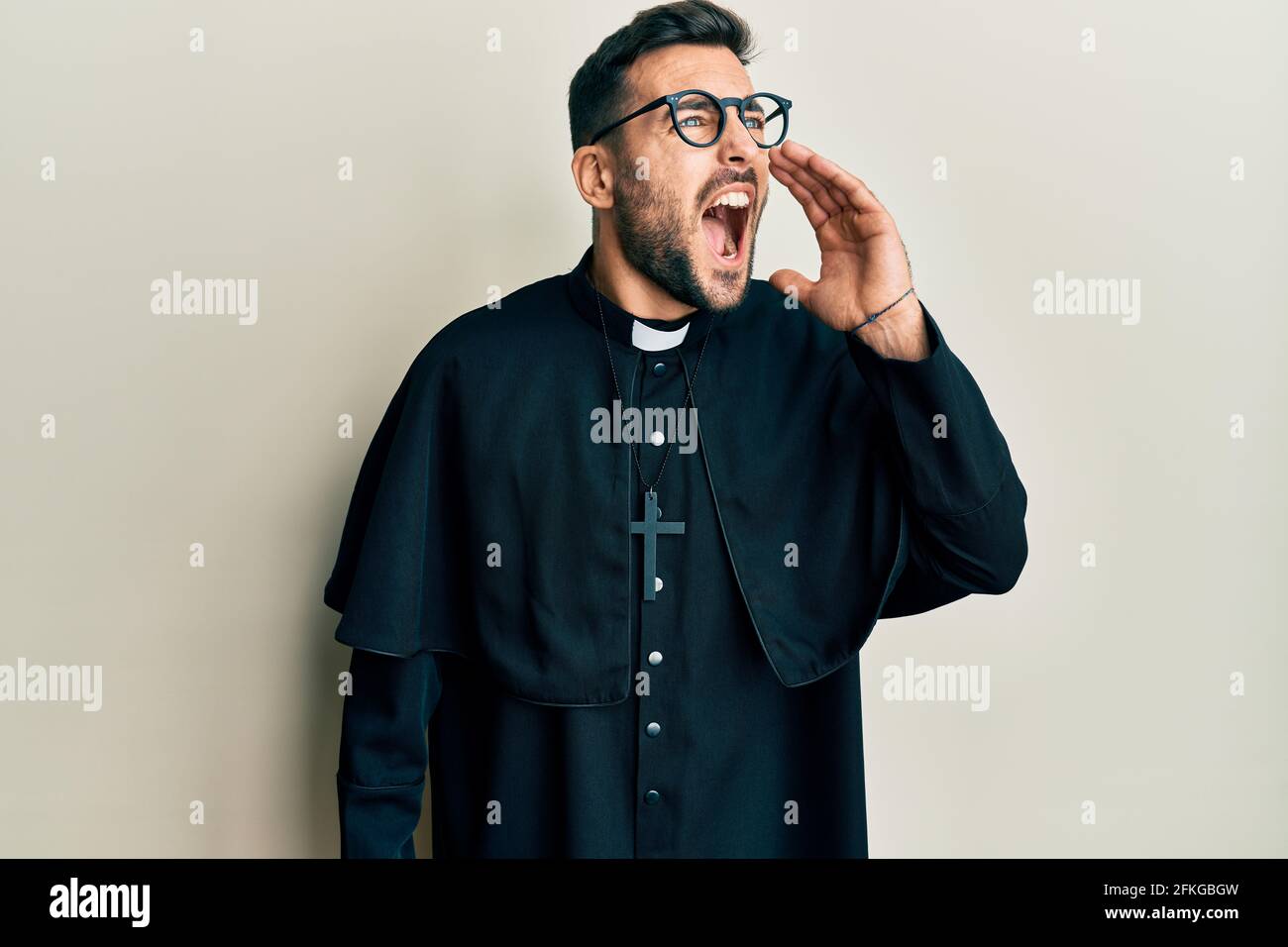 Young hispanic man wearing priest uniform standing over white ...