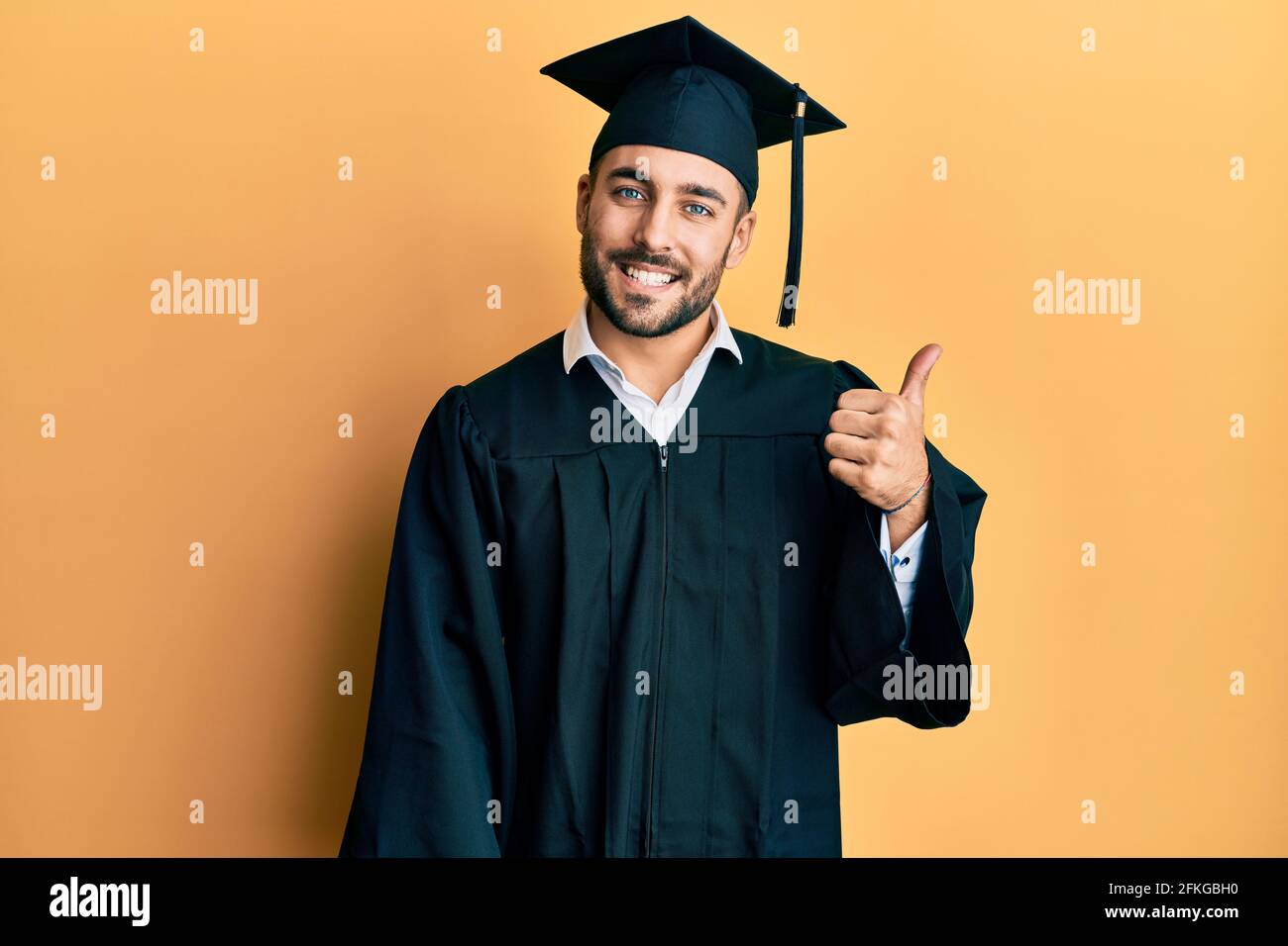 Young hispanic man wearing graduation cap and ceremony robe smiling ...
