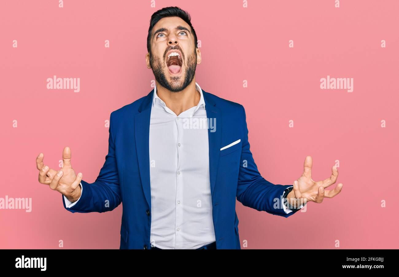 Young hispanic man wearing business jacket crazy and mad shouting and ...