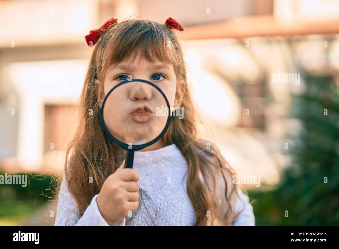 Adorable caucasian child girl kissing using loupe at the city Stock ...