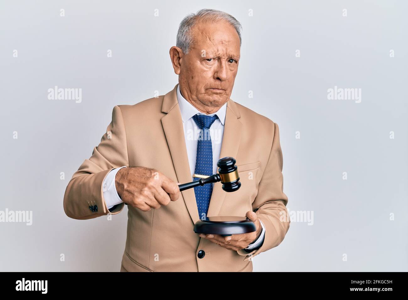 Senior caucasian judge man using gavel skeptic and nervous, frowning ...