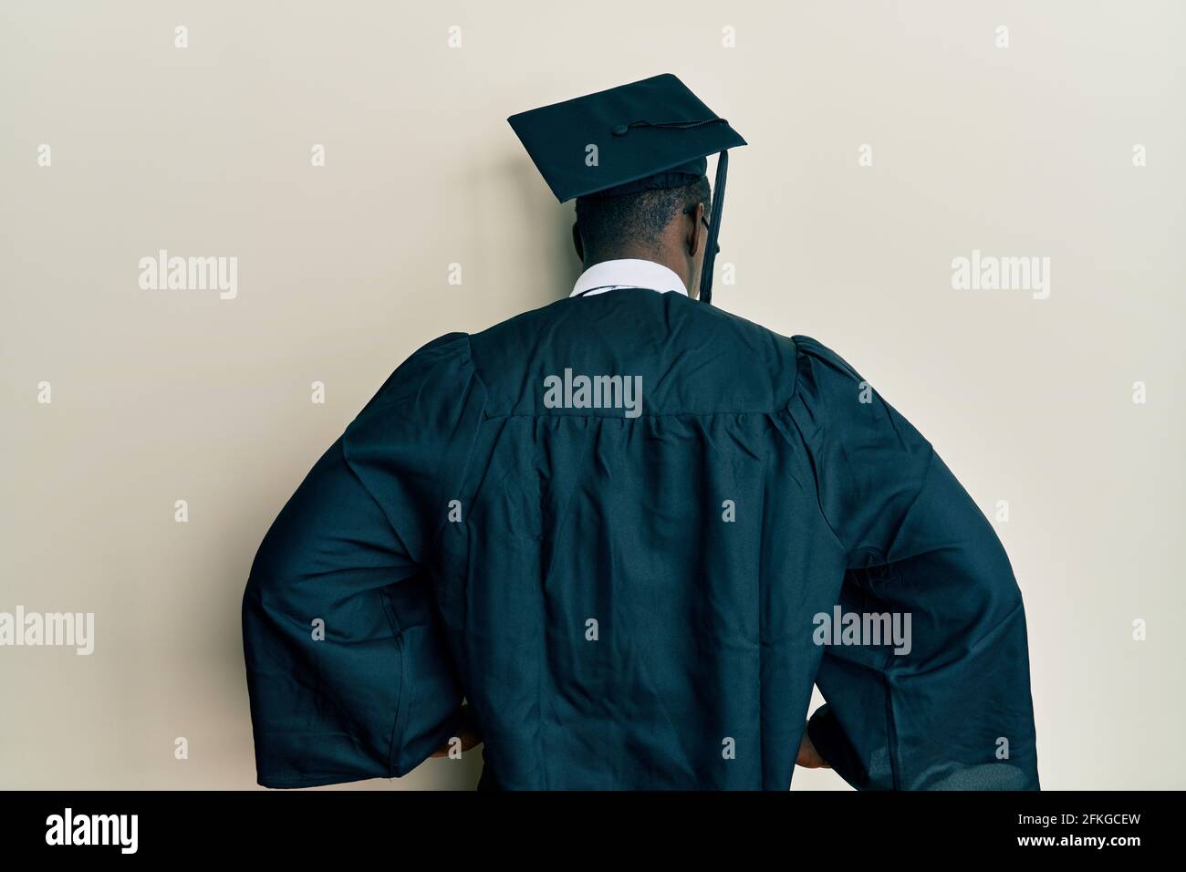 Handsome black man wearing graduation cap and ceremony robe standing ...