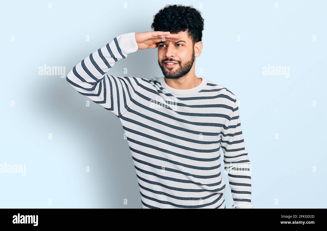 Young arab man with beard wearing casual striped sweater very happy and ...