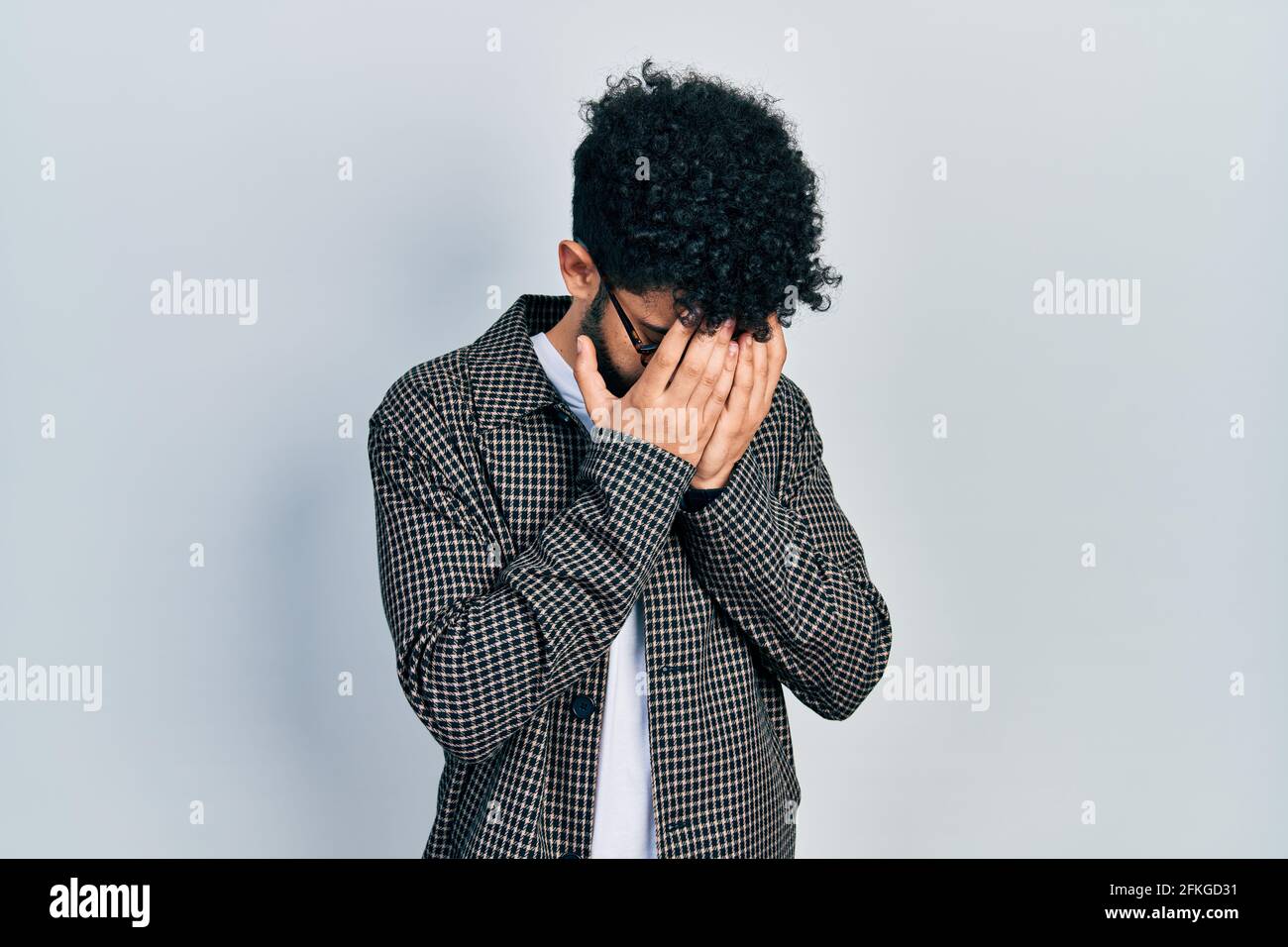 Young arab man with beard wearing glasses with sad expression covering ...